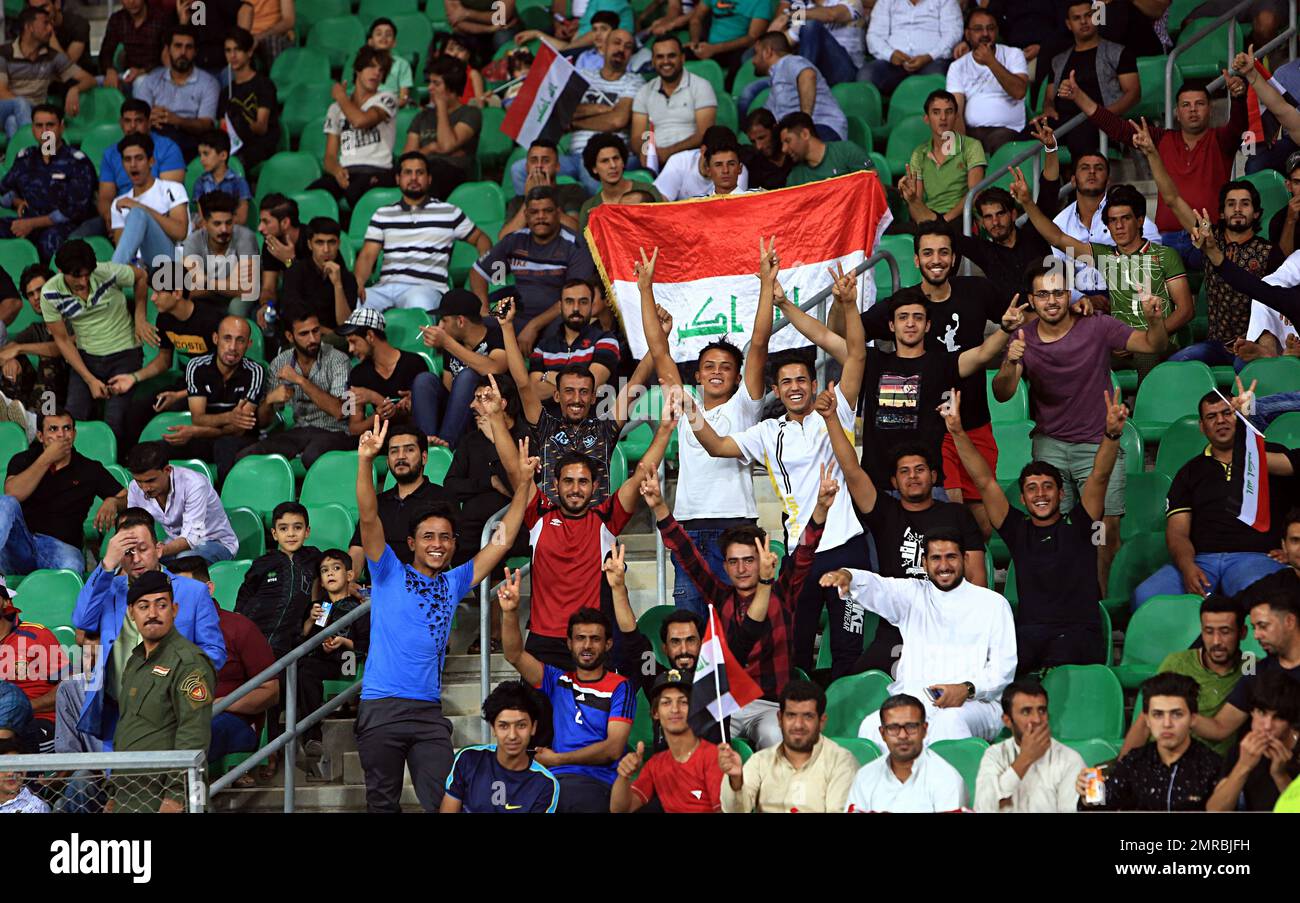 Iraqi soccer fans display national flags as they cheer during a ...