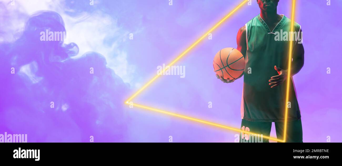 Midsection of african american male player with basketball by glowing ...