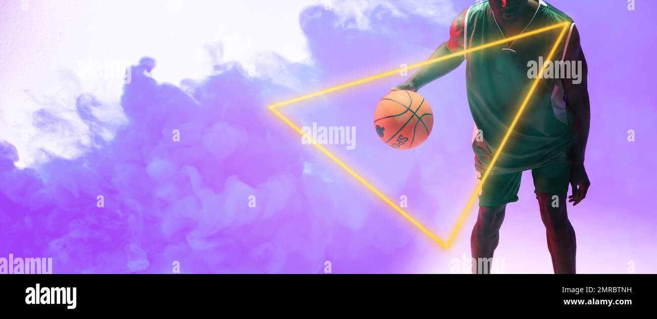 Midsection of african american male player with basketball by glowing ...