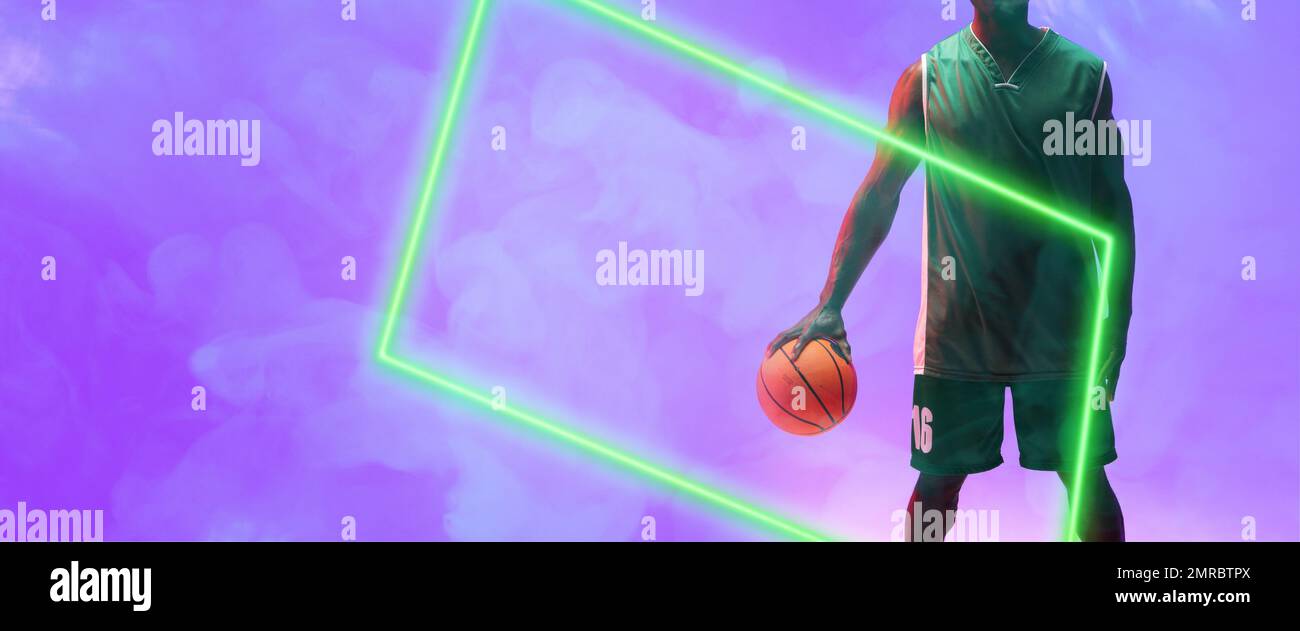 Midsection of african american male player with basketball by glowing ...