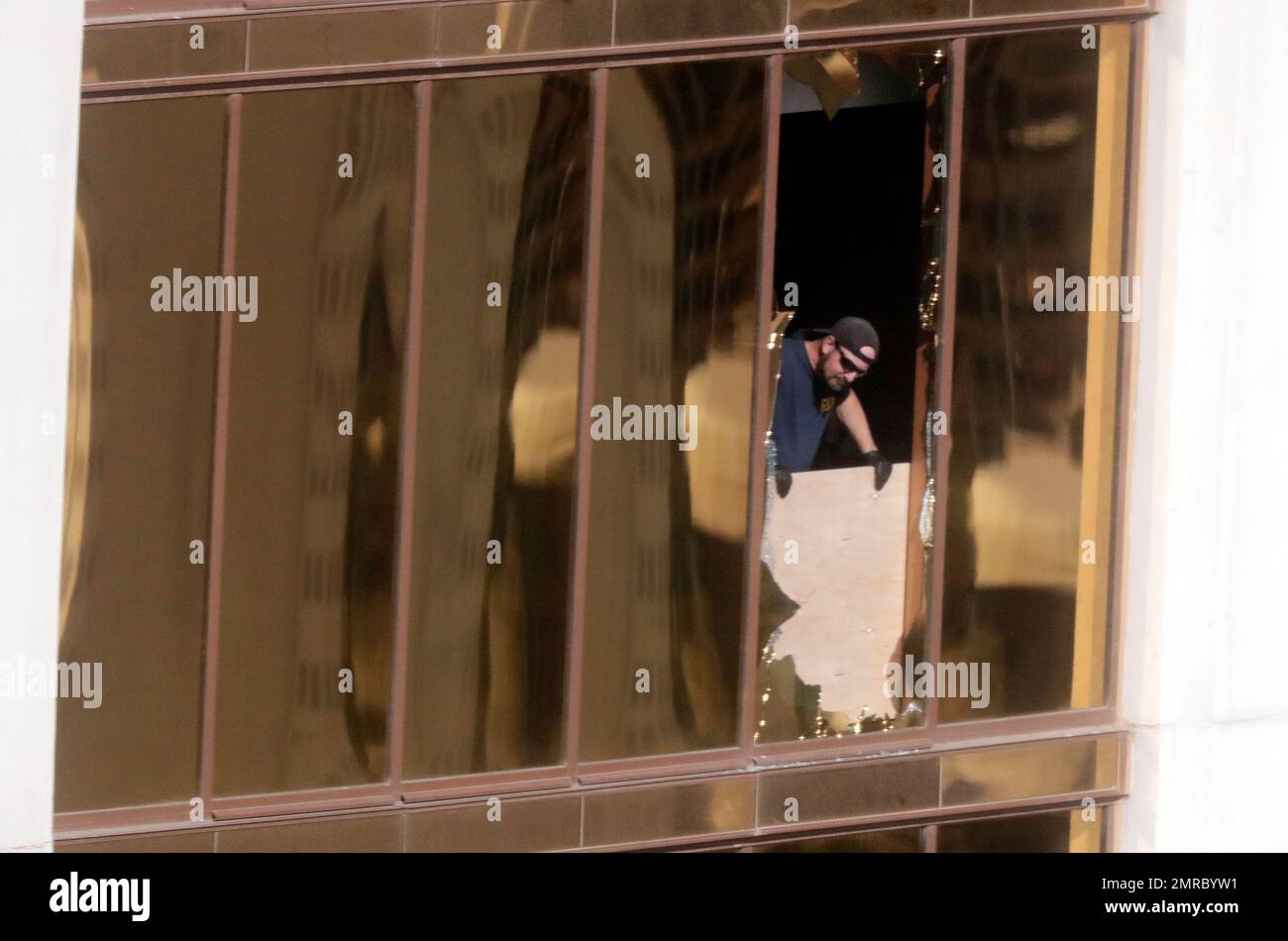 Agents from the FBI use binoculars from the broken window where a ...