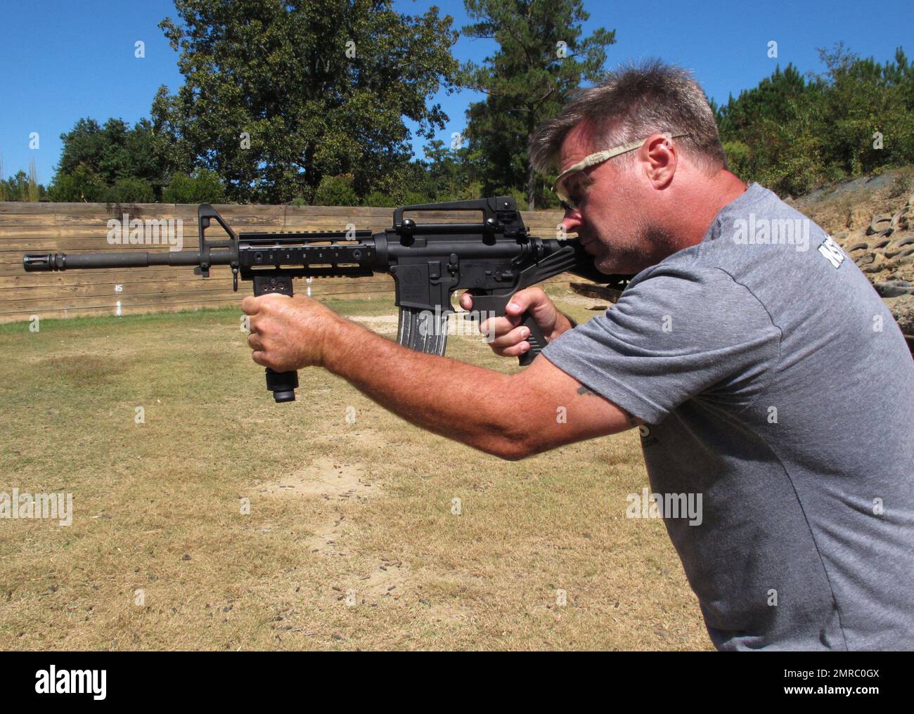 Shooting instructor Frankie McRae aims an AR-15 rifle fitted with a ...