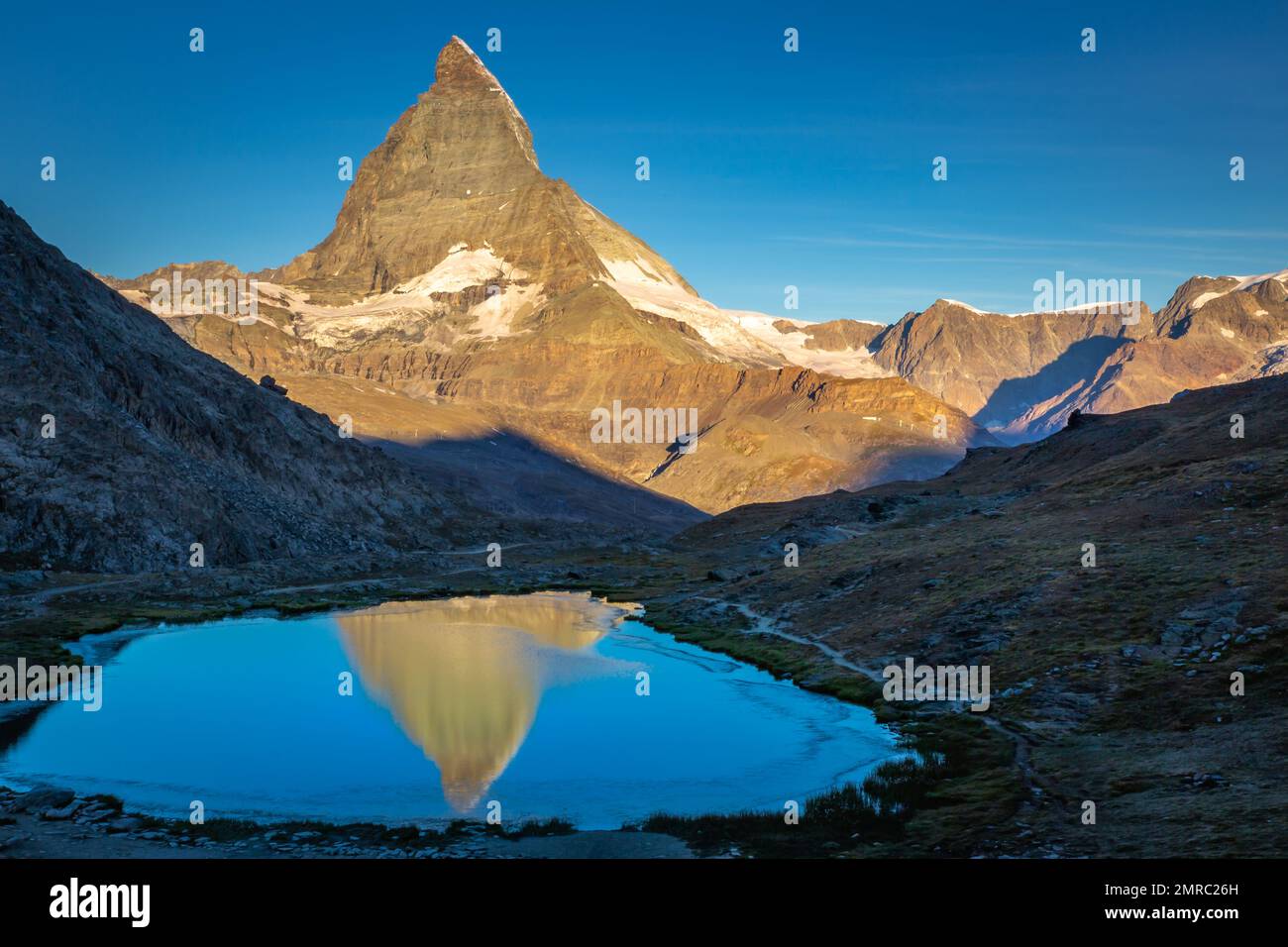 Reflection of the Matterhorn on blue lake at sunrise, Swiss Alps ...