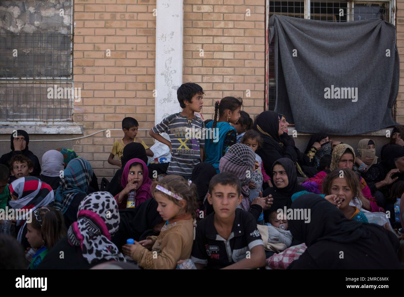 Women and children from Hawija sit outside a Kurdish screening center ...