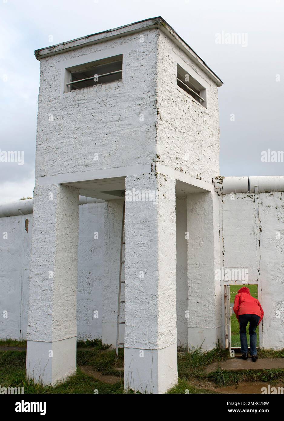 A visitor looks through a small gate in the former GDR border wall in ...