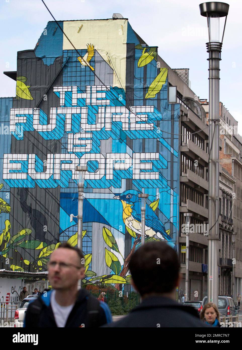 People walk past a giant mural on a main avenue in the EU quarter of ...