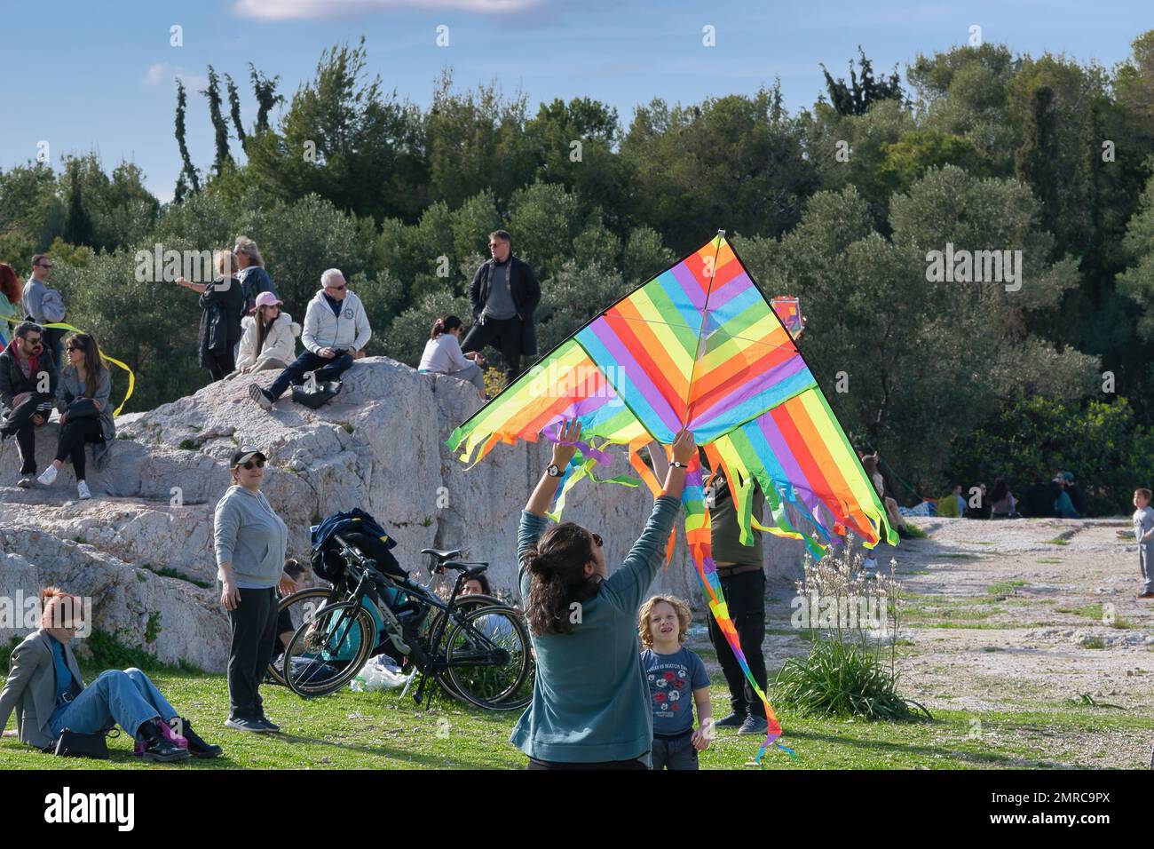 A mother and a child flying a colorful kite on a sunny day in the city ...