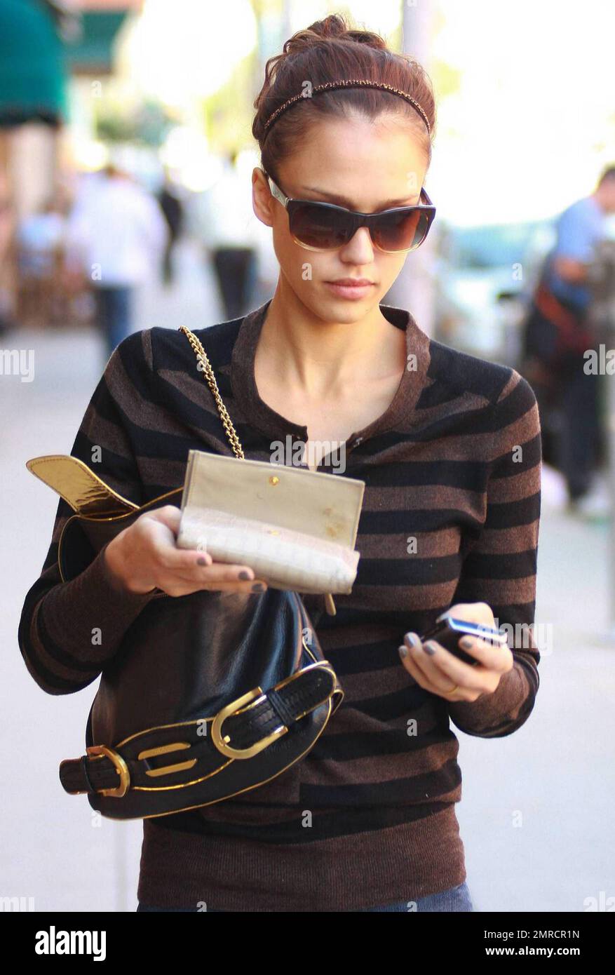Actress Jessica Alba checks messages on her cellphone while strolling ...