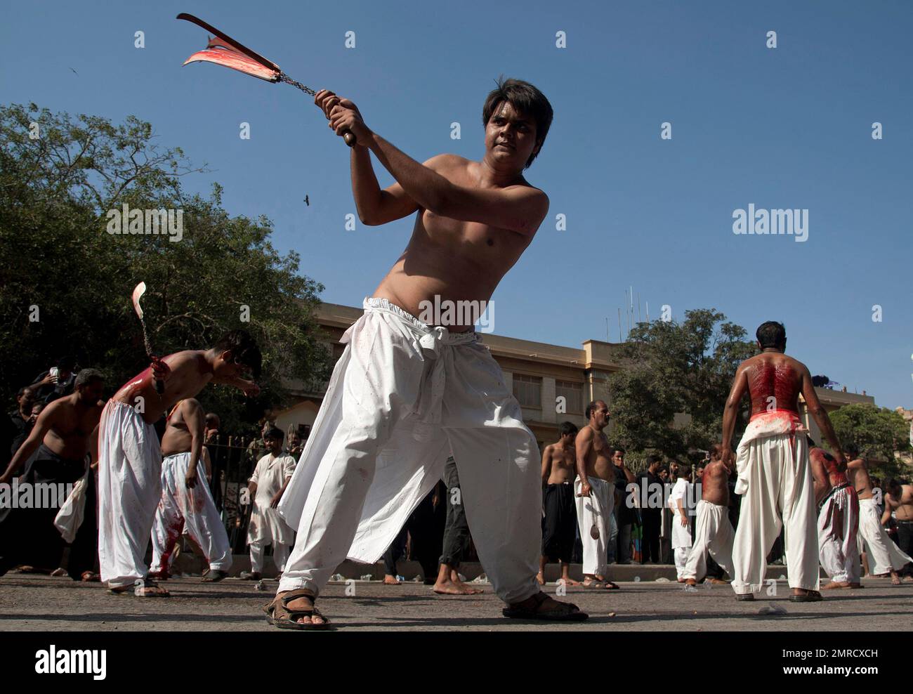 Shiite Muslims flagellate themselves with knives attached to chains ...