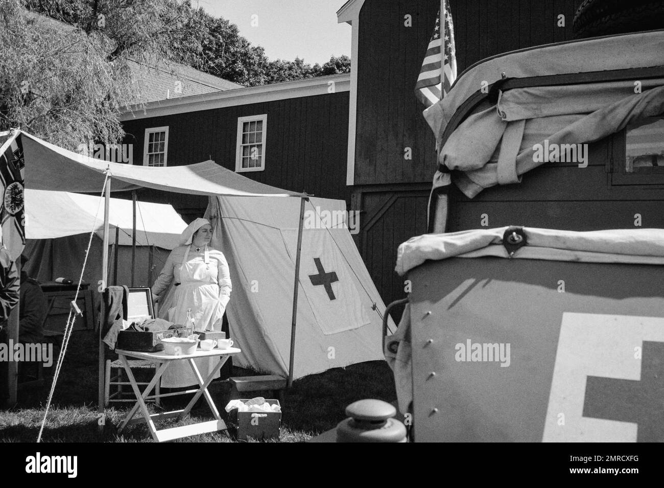 A WWI Red Cross nurse stand ready outside or surgical tent with ...