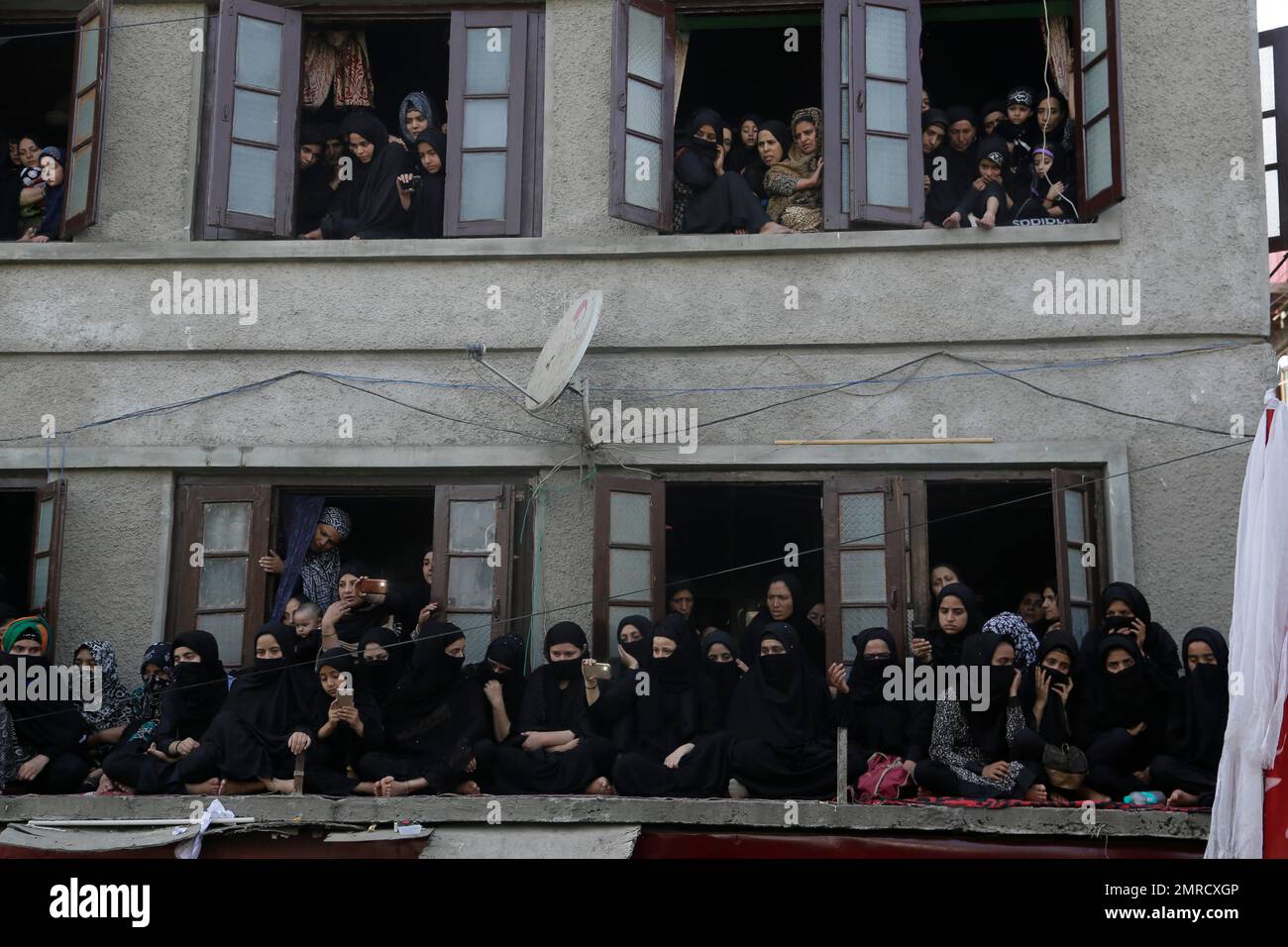 Kashmiri Shiite Muslims watch from window of a residential building, a ...
