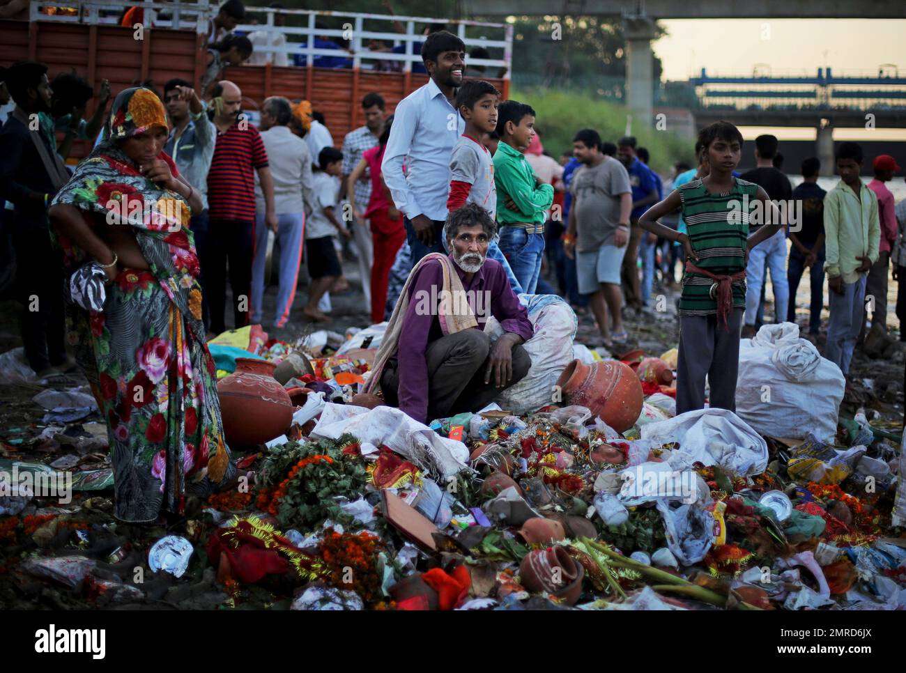 An Indian rag picker squats on a pile of discarded items used in ...