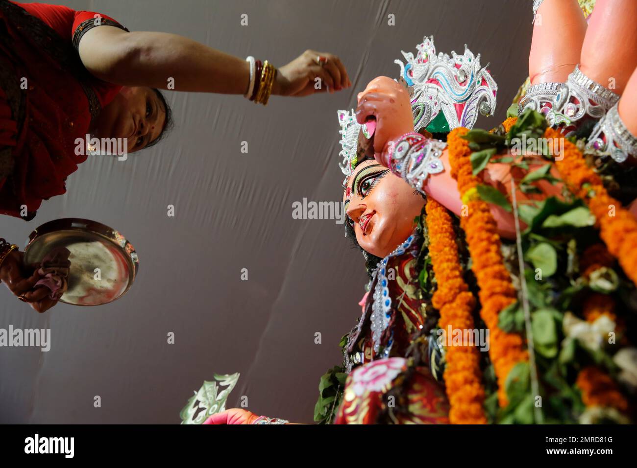 A Hindu woman performs rituals in front of an idol of Hindu goddess ...