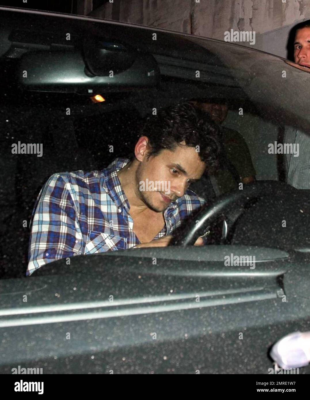 Musician John Mayer signs a guitar for a fan as he leaves the Hotel ...