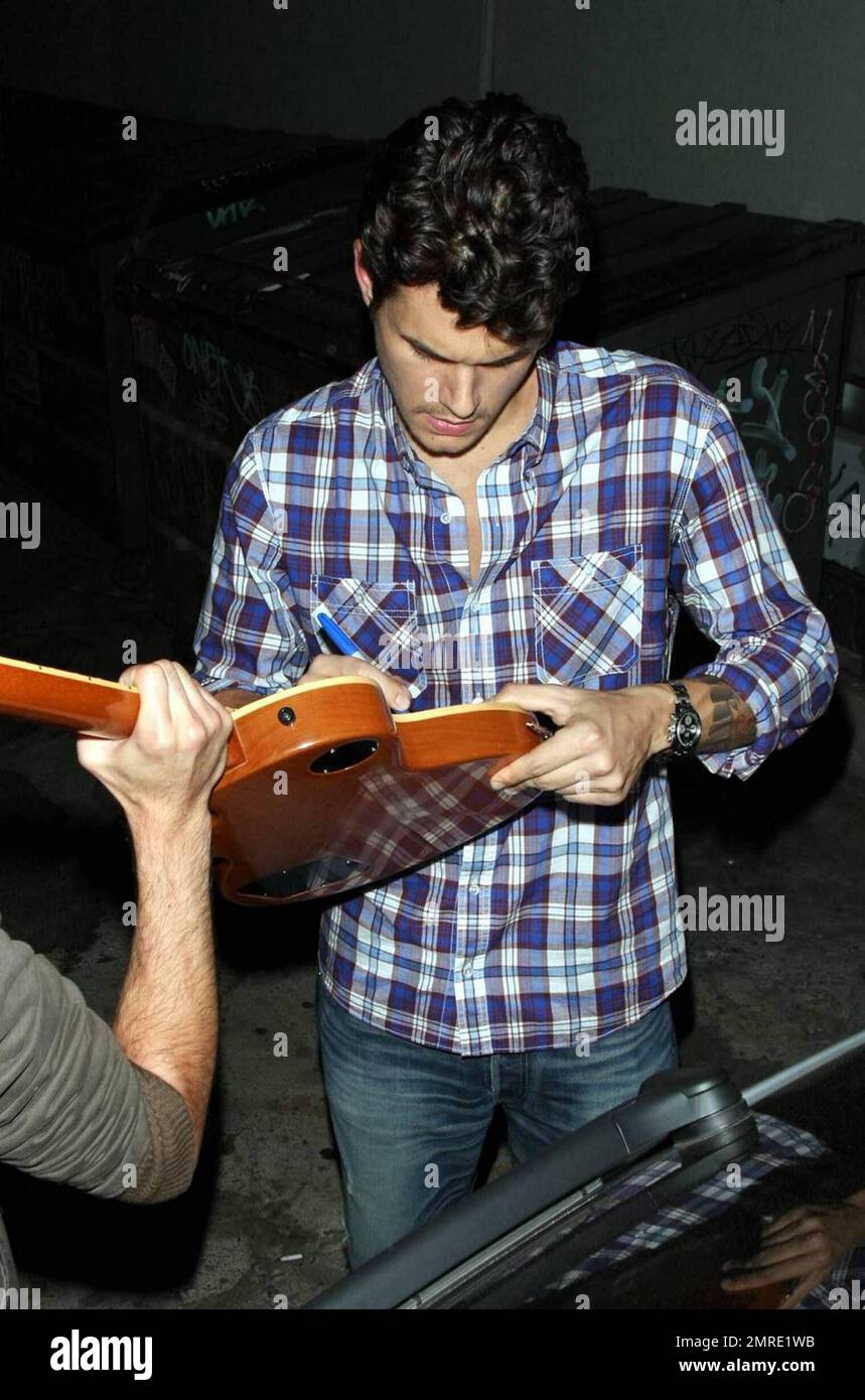 Musician John Mayer signs a guitar for a fan as he leaves the Hotel ...