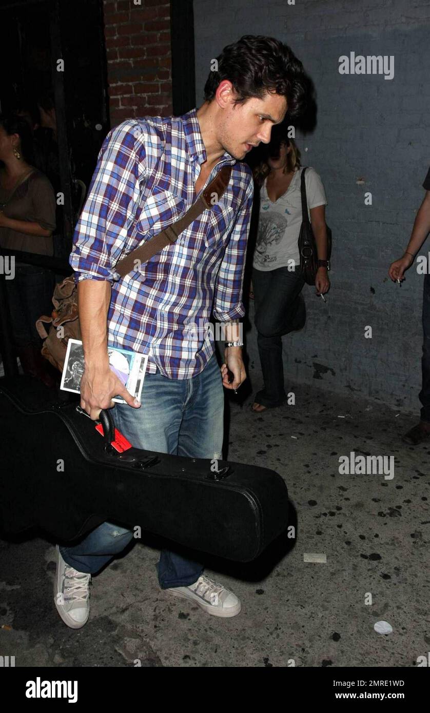 Musician John Mayer signs a guitar for a fan as he leaves the Hotel ...