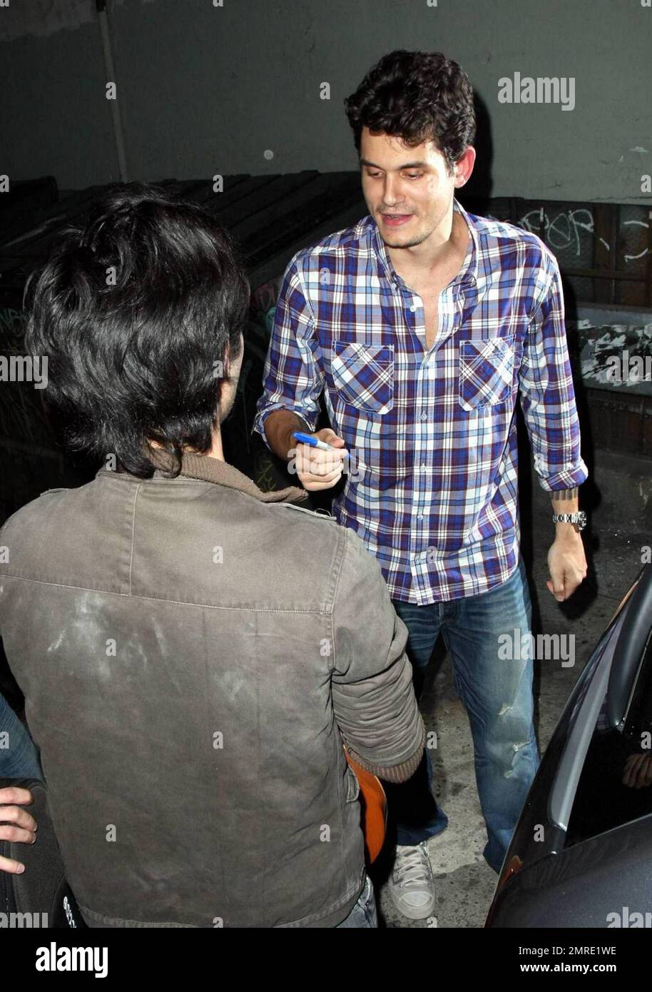 Musician John Mayer signs a guitar for a fan as he leaves the Hotel ...