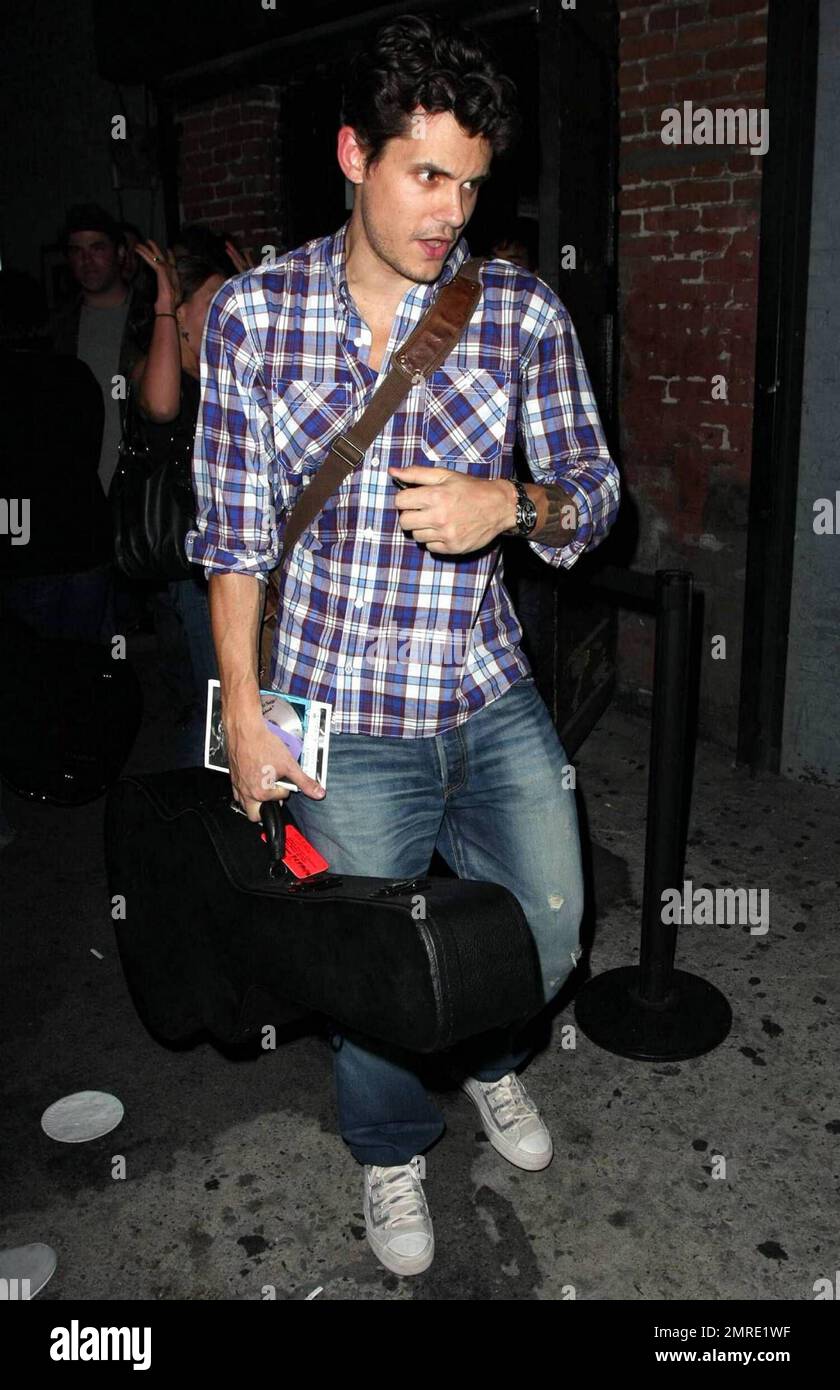 Musician John Mayer signs a guitar for a fan as he leaves the Hotel ...