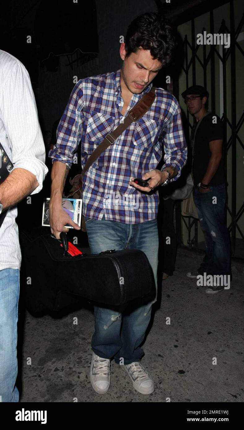 Musician John Mayer signs a guitar for a fan as he leaves the Hotel ...