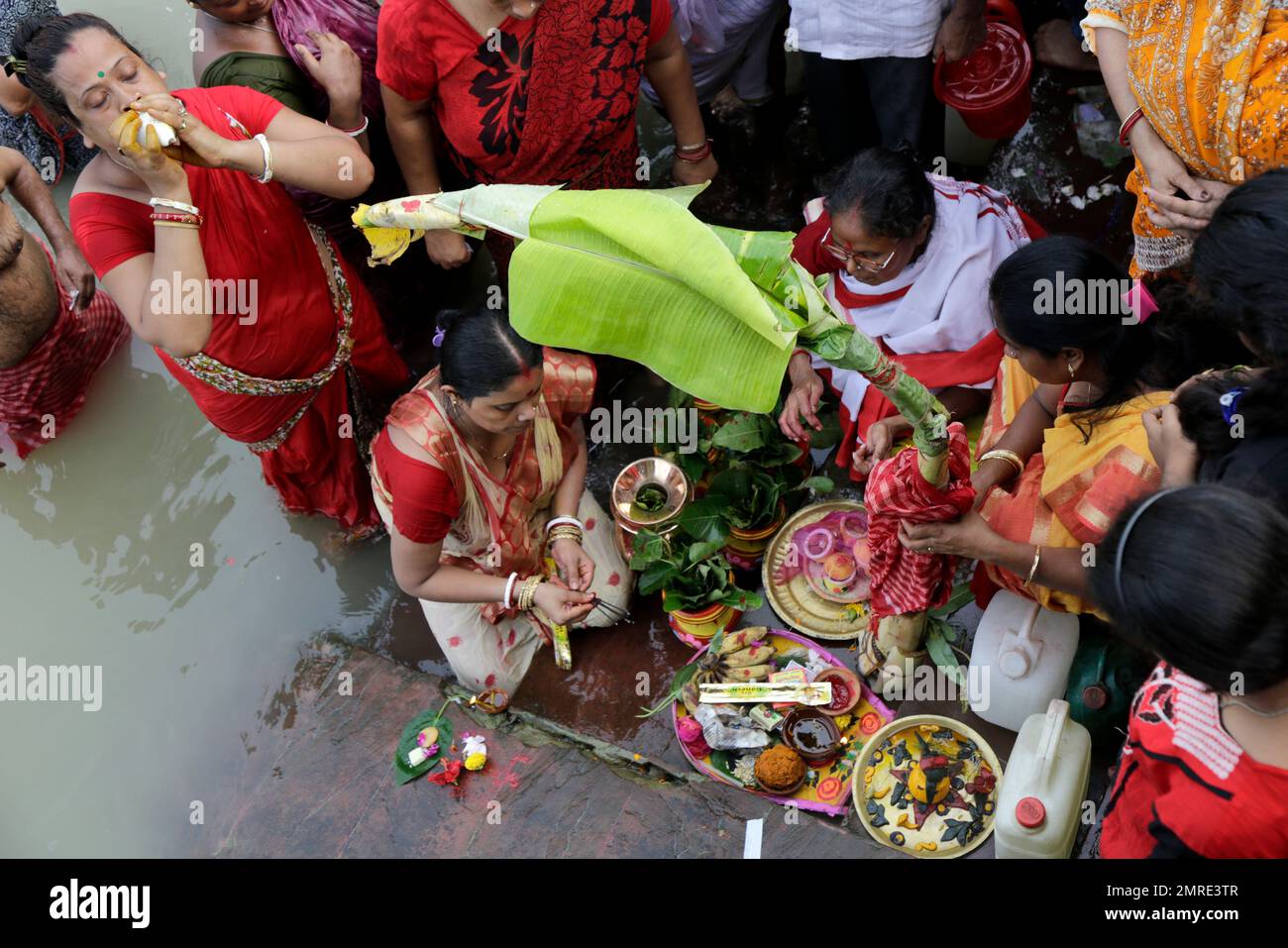 A married Hindu woman blows a conch as others perform rituals with a ...