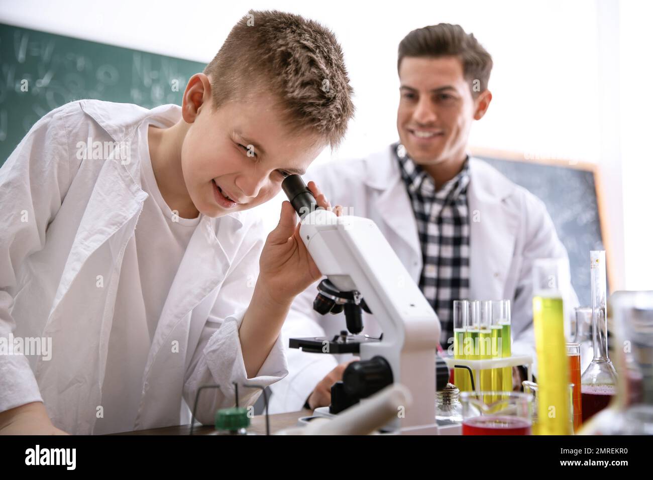 Teacher with pupil using microscope in chemistry class Stock Photo - Alamy