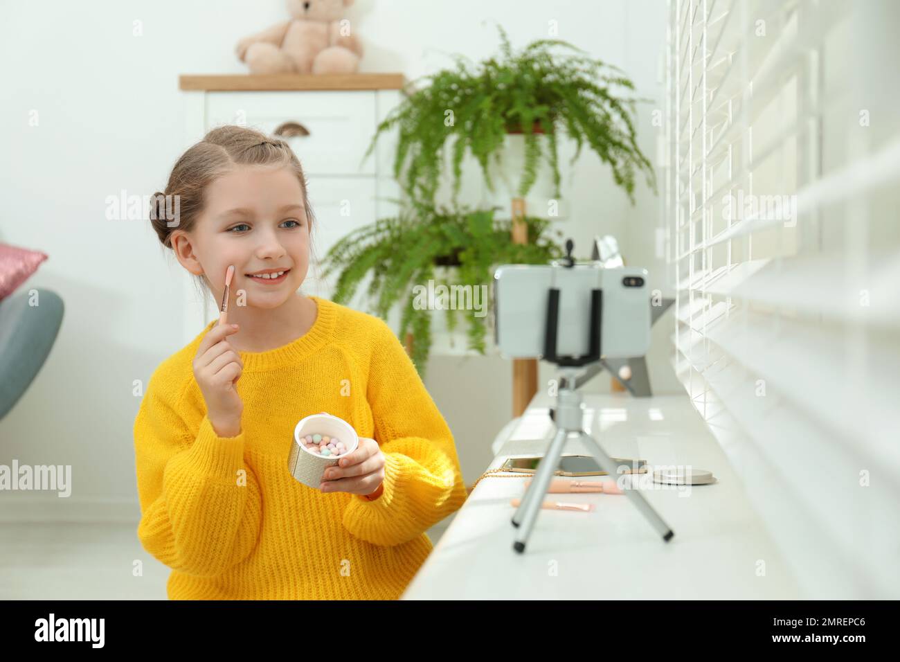 Cute little blogger with cosmetics recording video at home Stock Photo ...