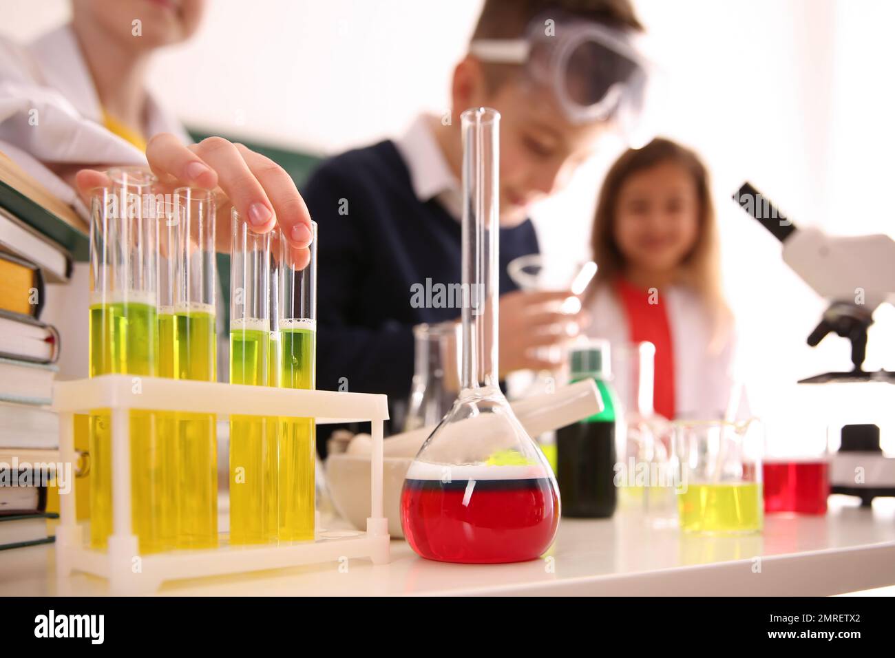 Smart pupils making experiment in chemistry class, focus on flask with ...
