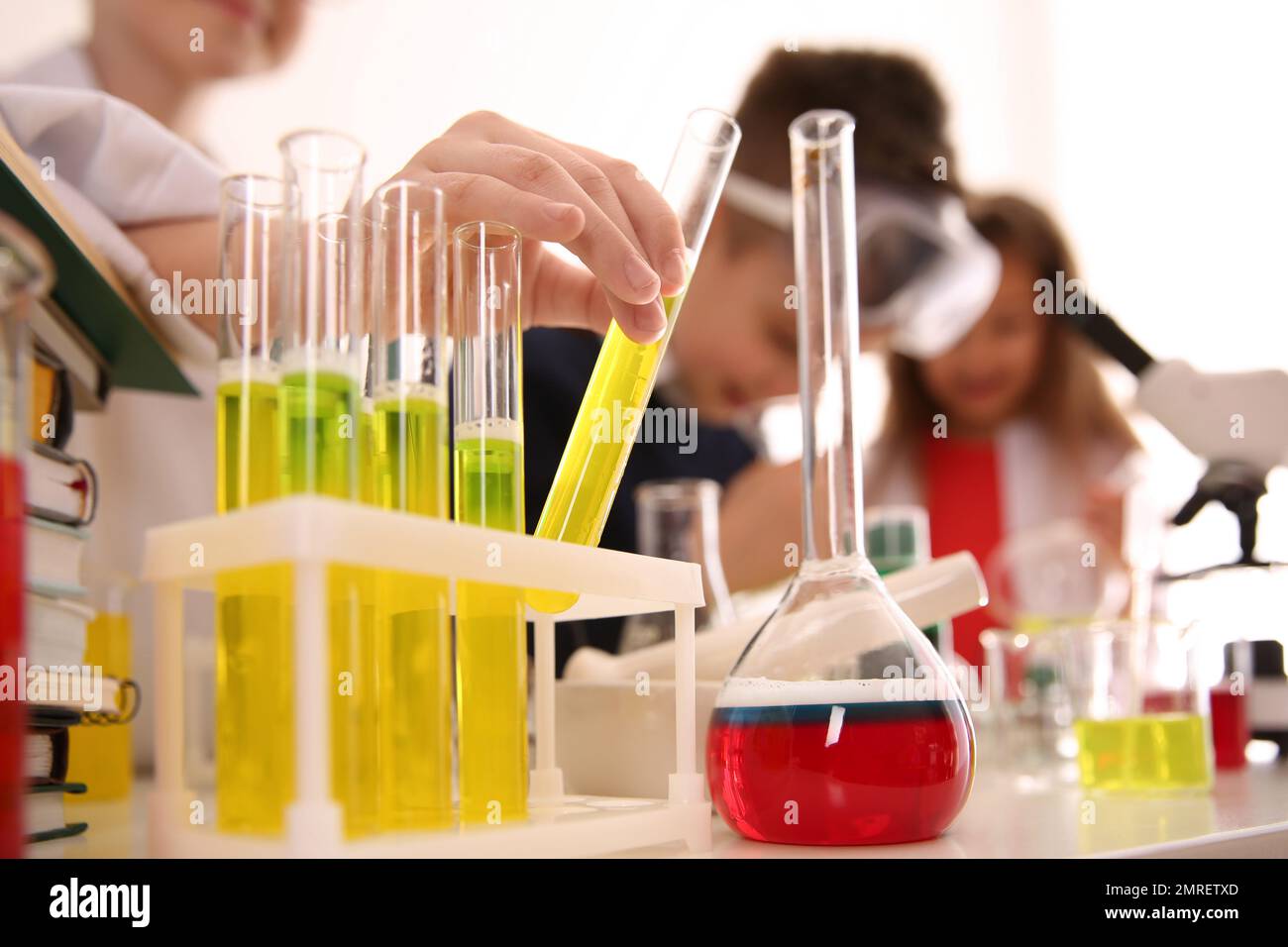Smart pupils making experiment in chemistry class, focus on flask with ...