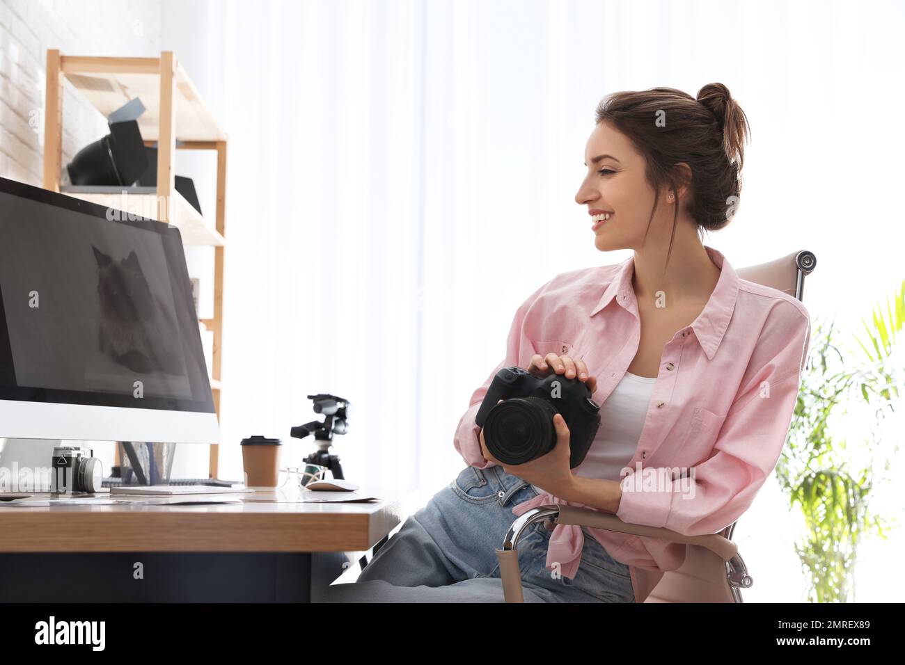 Professional photographer with camera working at table in office Stock ...