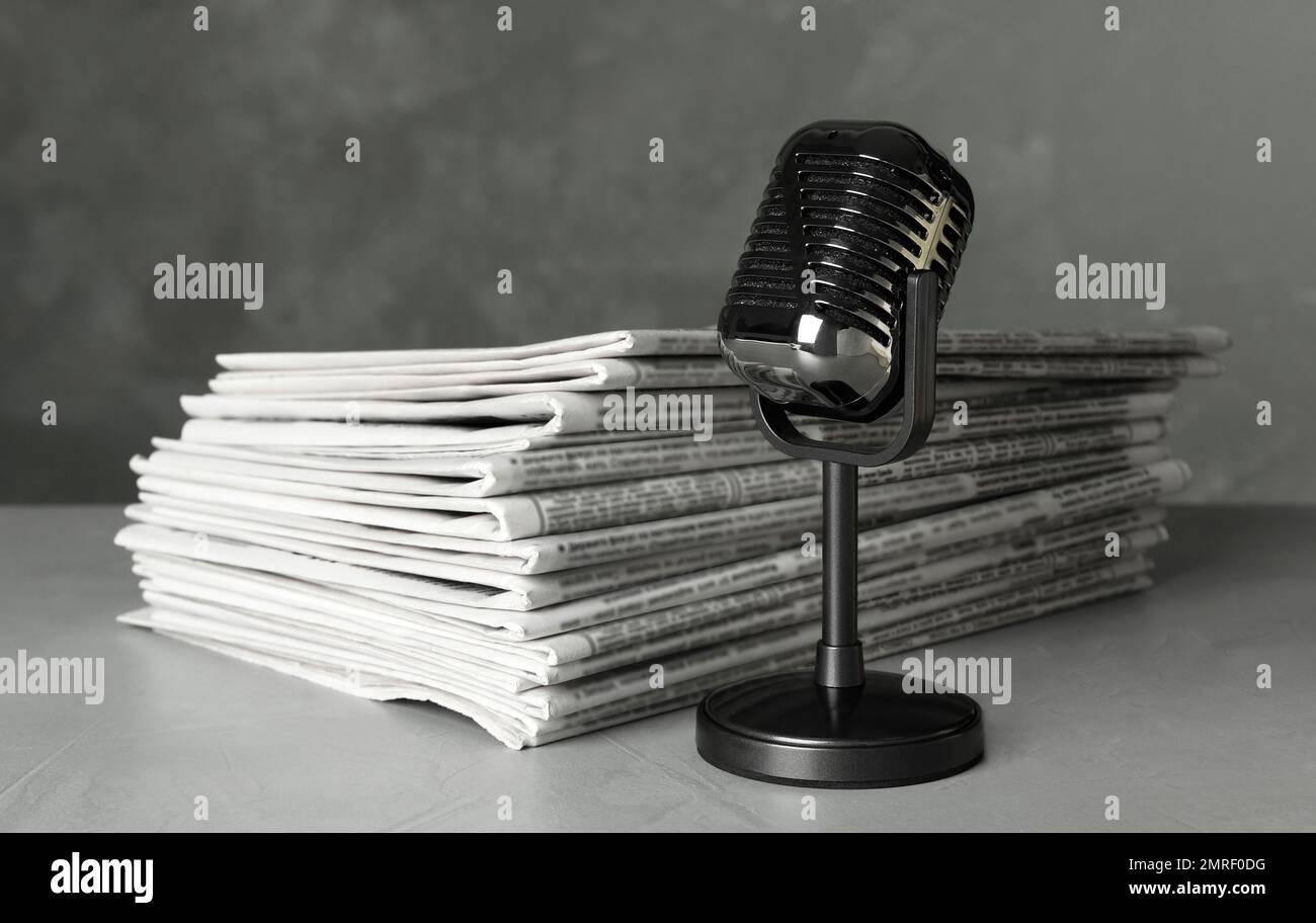 Newspapers and vintage microphone on light grey stone table. Journalist ...