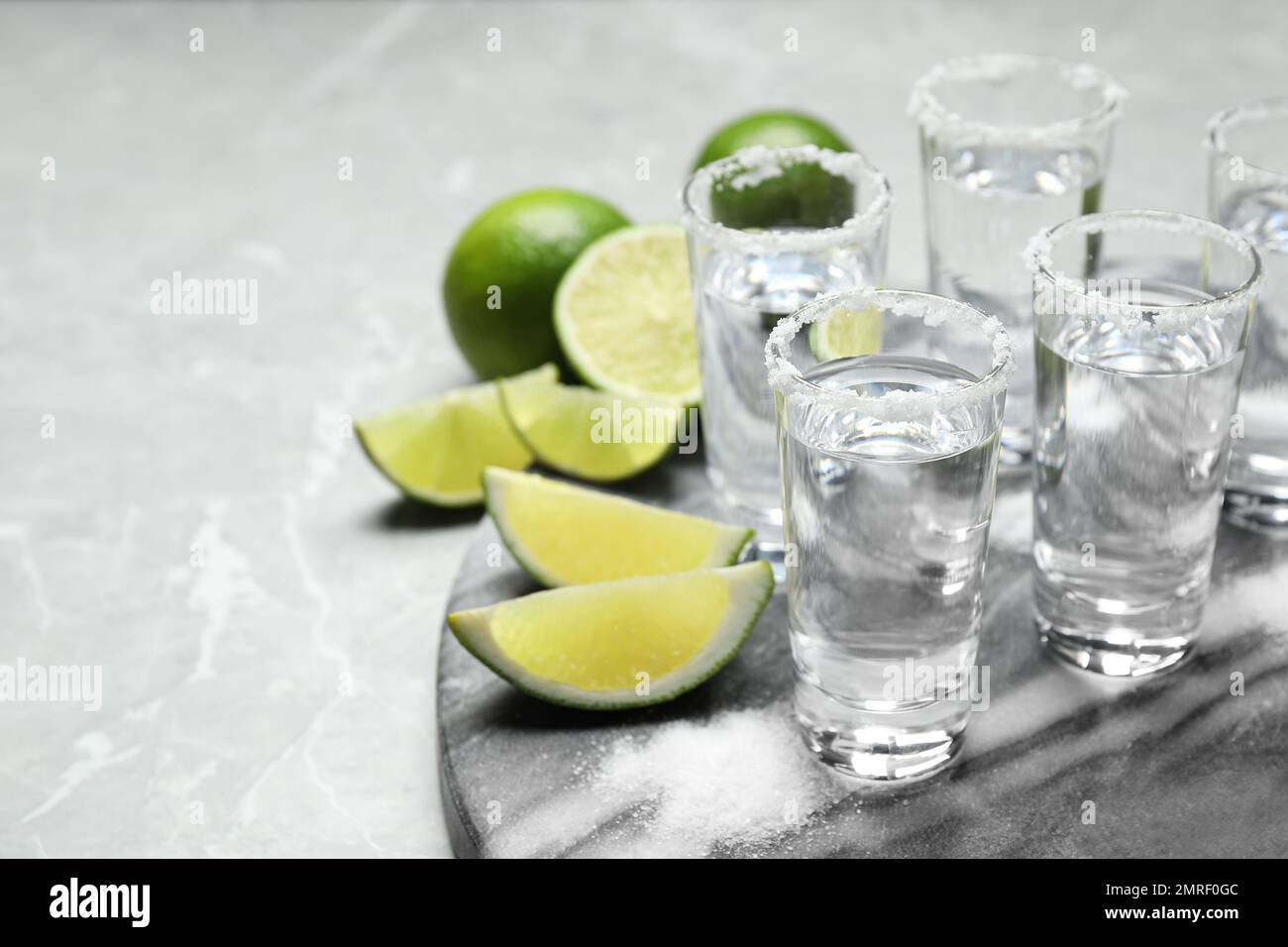 Mexican Tequila shots, lime slices and salt on grey marble table Stock ...