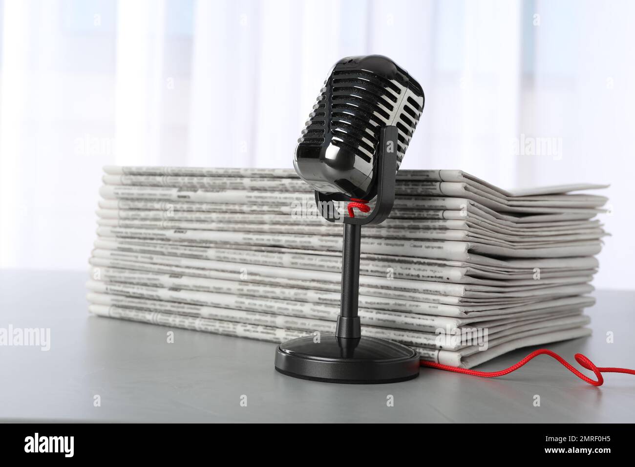 Newspapers and vintage microphone on grey table. Journalist's work ...