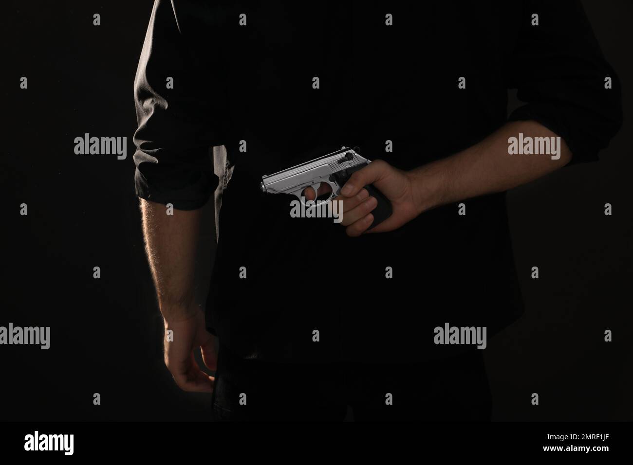 Professional killer with gun on black background, closeup Stock Photo ...