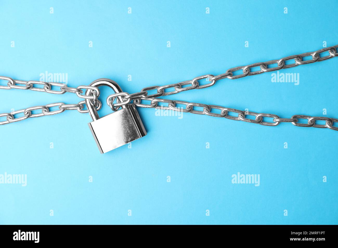 Steel padlock and chains on light blue background, top view. Safety ...