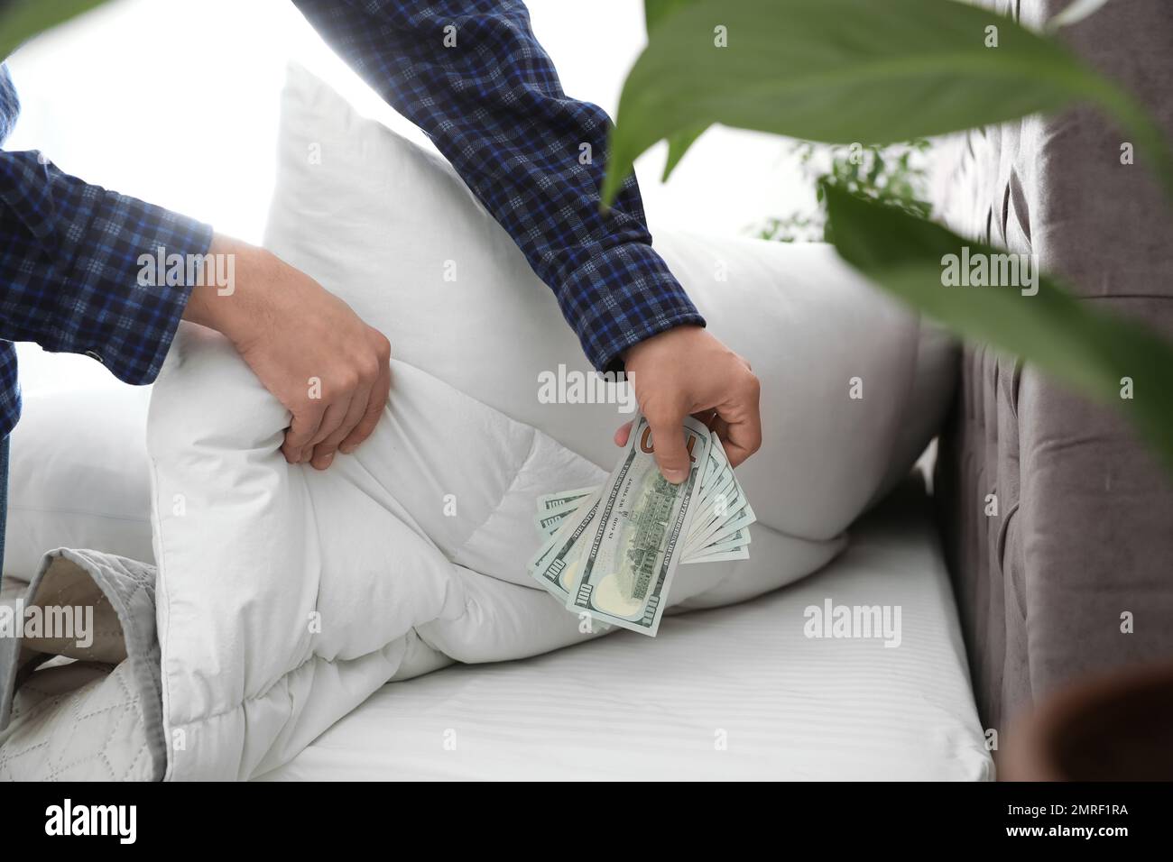 Man hiding dollar banknotes under blanket in bedroom, closeup. Money ...