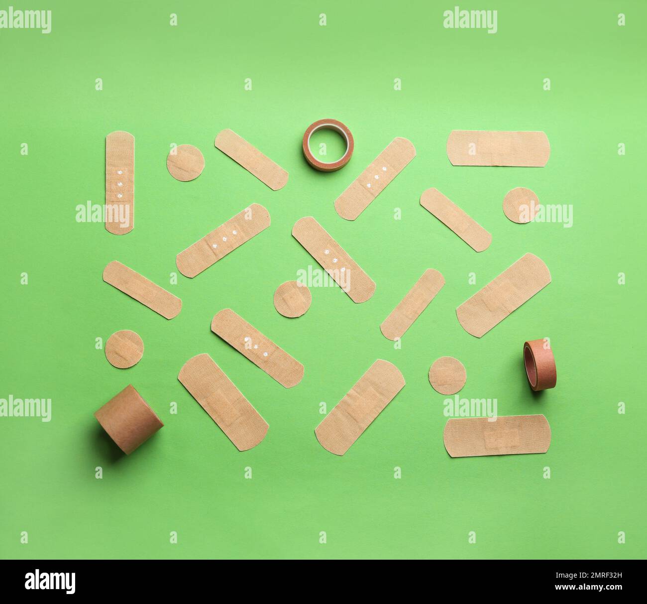 Different types of sticking plasters on green background, flat lay ...