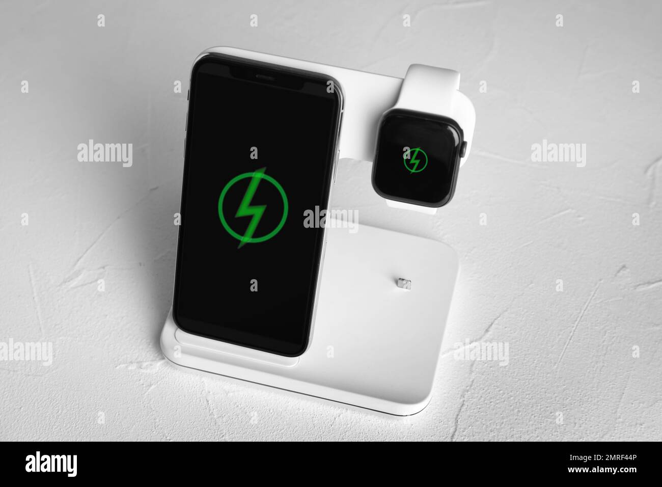 Mobile phone and smartwatch charging with wireless pad on white stone ...