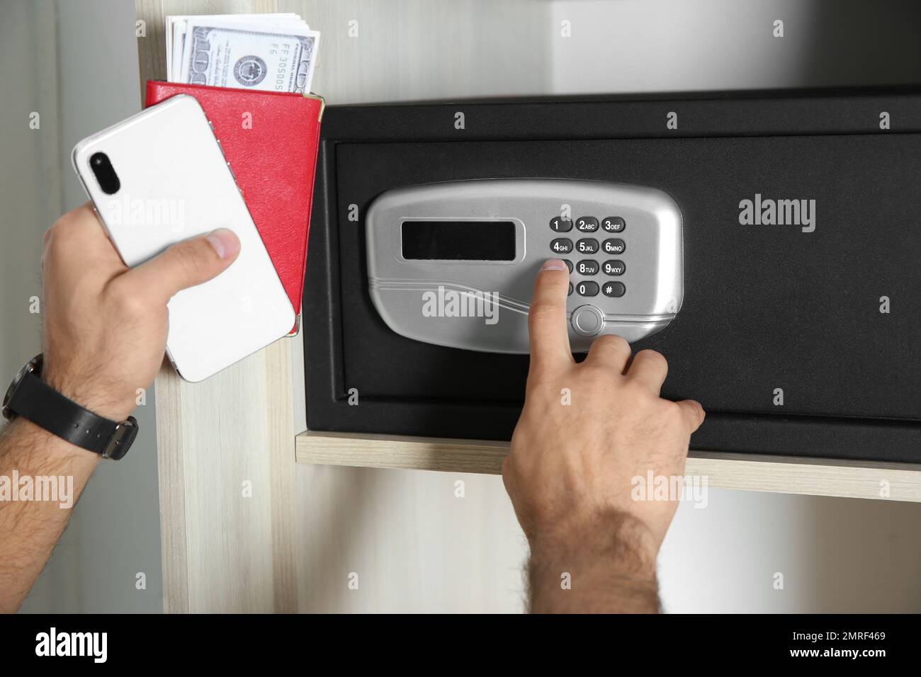 Man opening black steel safe with electronic lock at hotel, closeup ...