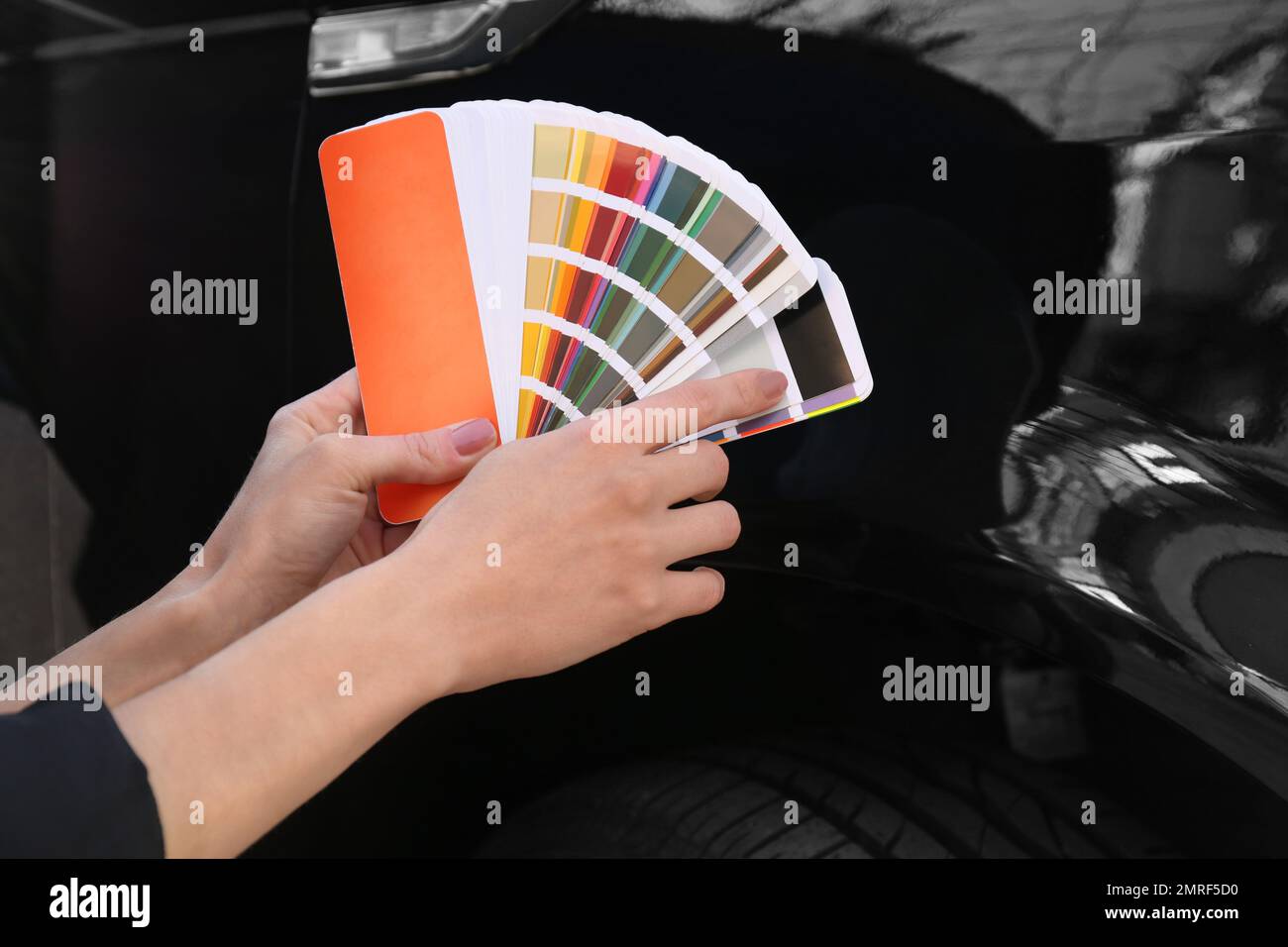 Woman with palette samples choosing color for painting car, closeup ...