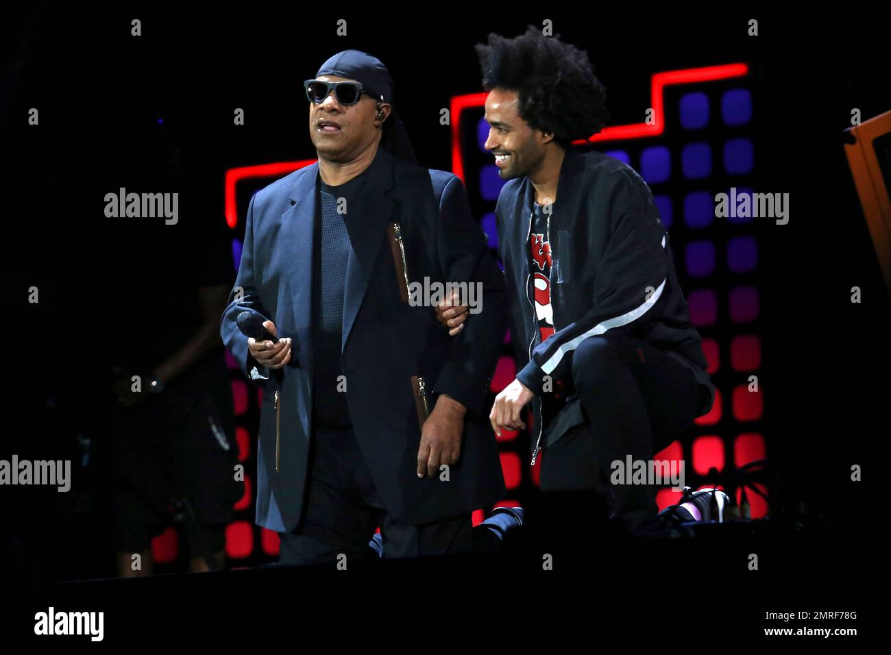 Stevie Wonder, left, kneels on stage next to his son Kwame Morris ...