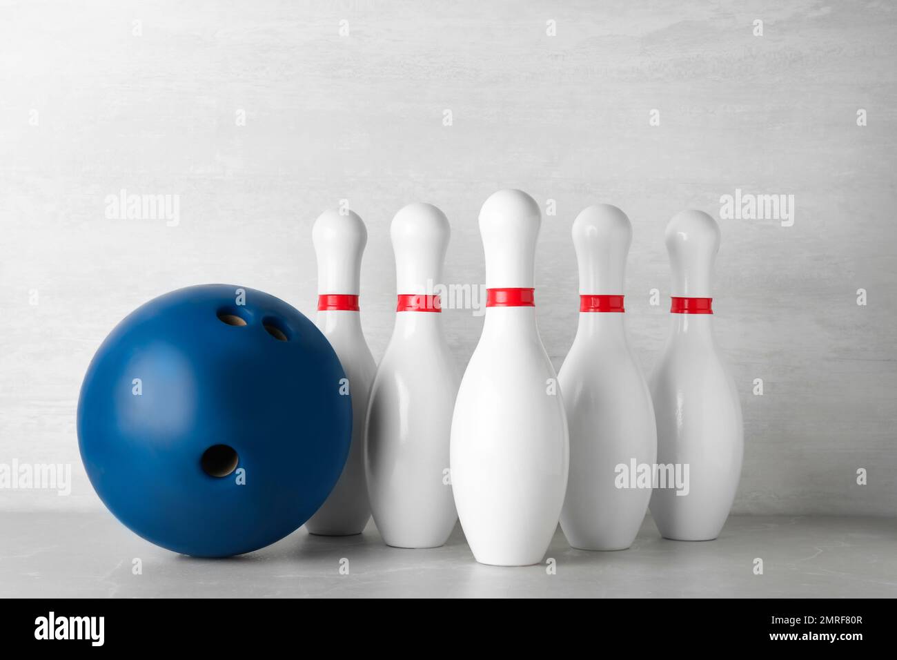 Blue bowling ball and pins on light grey marble table Stock Photo - Alamy