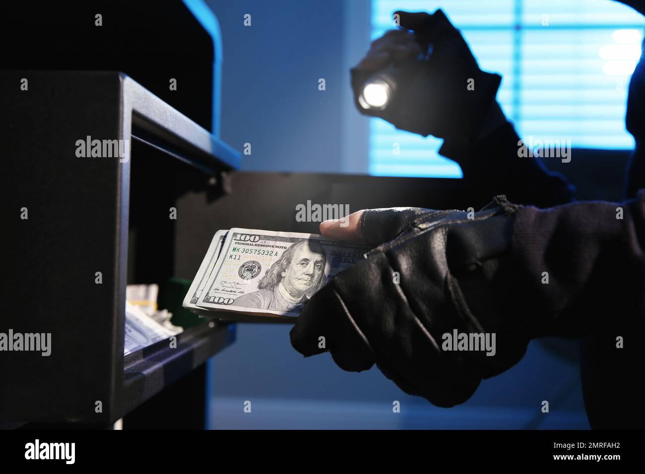 Thief taking money out of steel safe indoors at night, closeup Stock ...