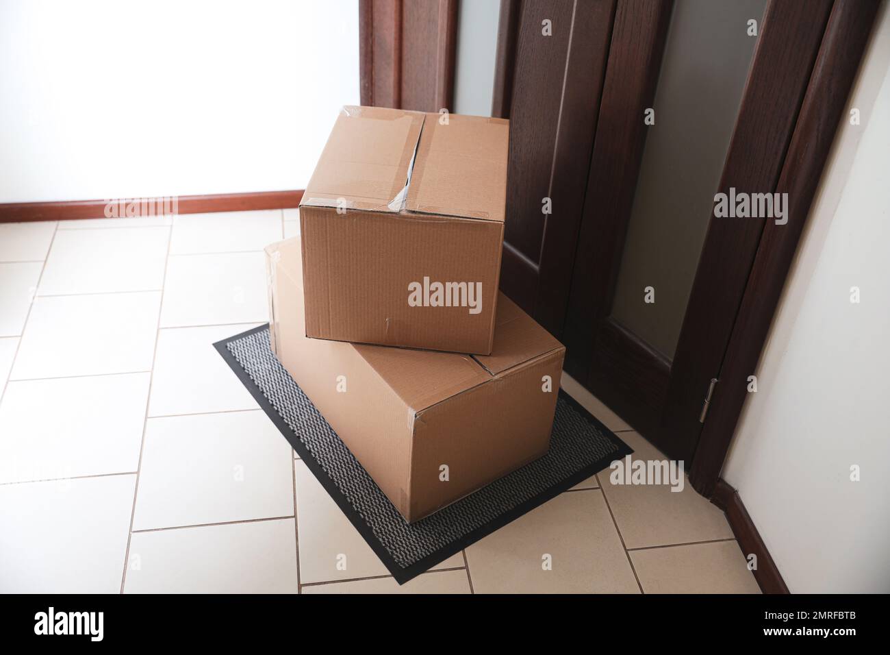 Cardboard boxes on rug near door. Parcel delivery service Stock Photo ...