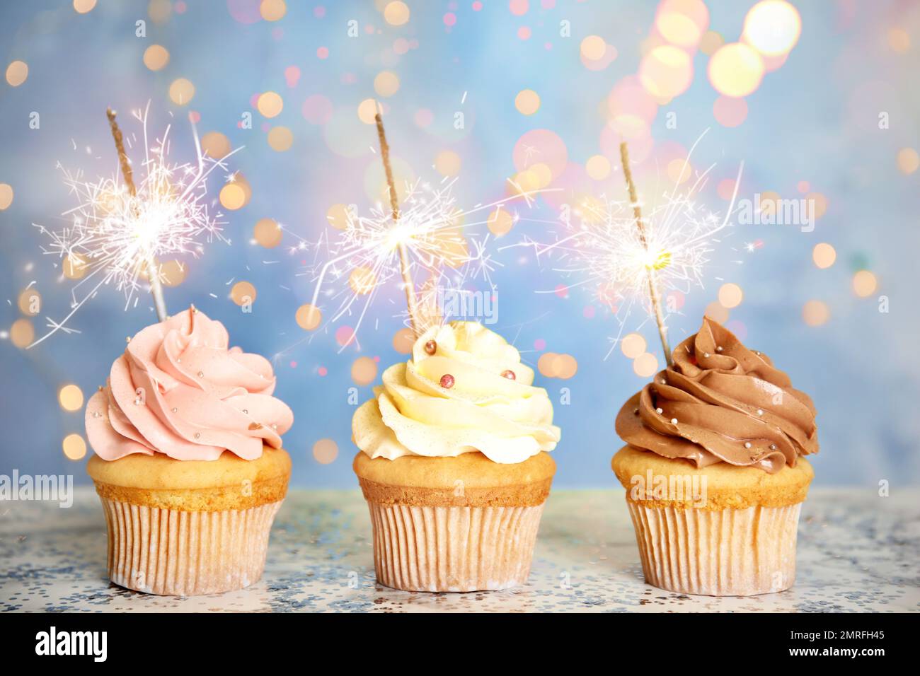 Delicious birthday cupcakes with sparklers on table against blurred lights Stock Photo - Alamy
