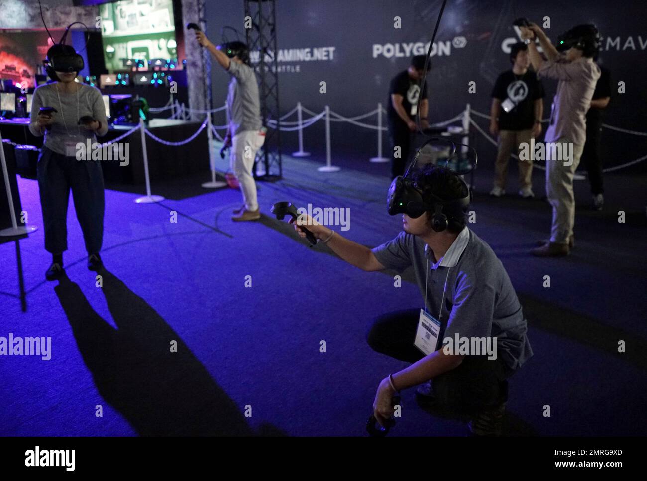 Visitors try out a game with a virtual reality headset device at the ...