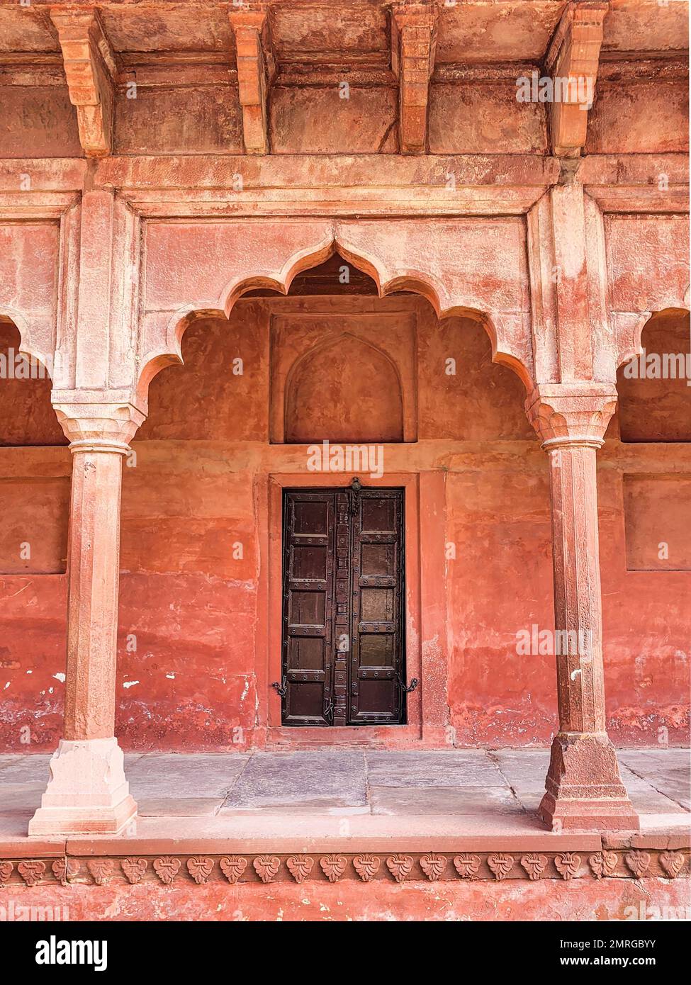 A vertical shot of red sandstone architecture with columns and wooden ...