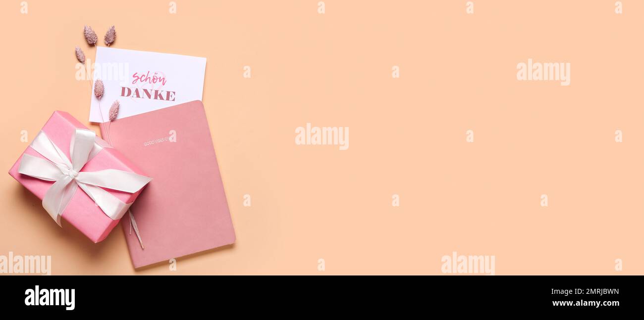 Card with text SCHON DANKE, notebook, gift and floral decor on orange ...