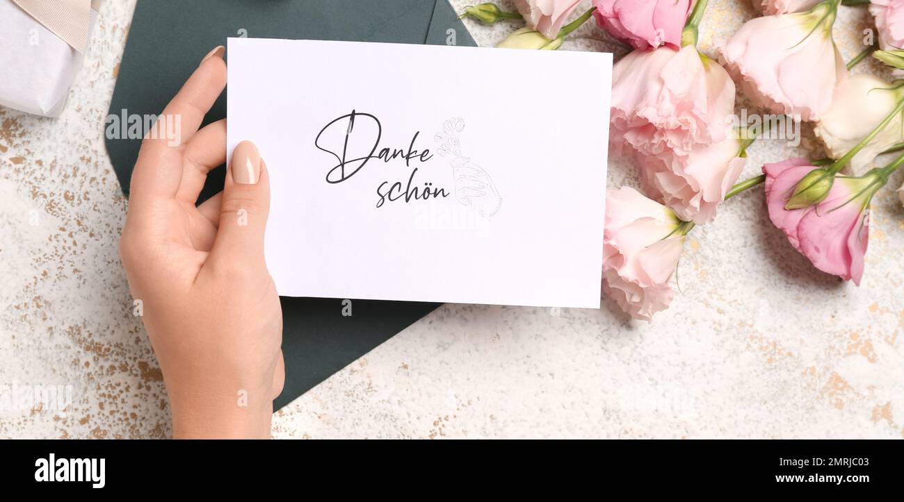 Female hand holding card with text DANKE SCHON, envelope and eustome ...