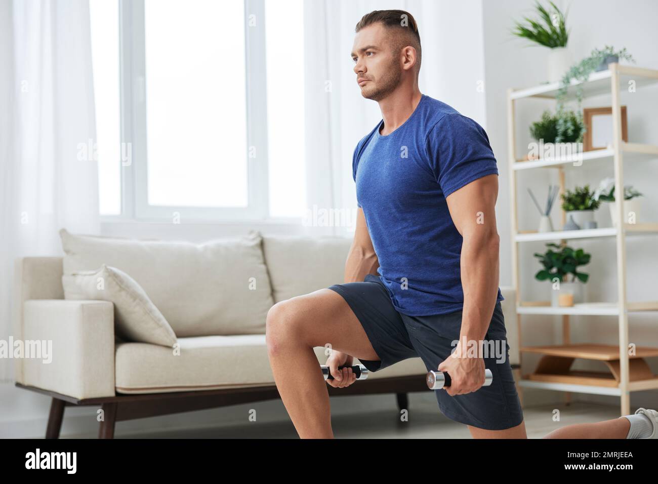 Man sportsman training at home with dumbbells, exercises for arms and ...