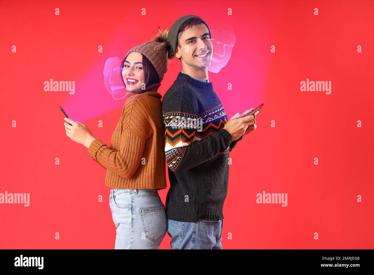 Happy young couple with mobile phones using facial recognition system ...